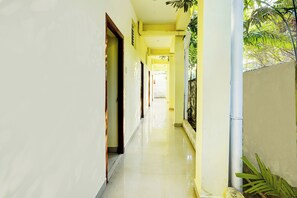 Um corredor com piso de azulejos, parede branca e parede amarela.