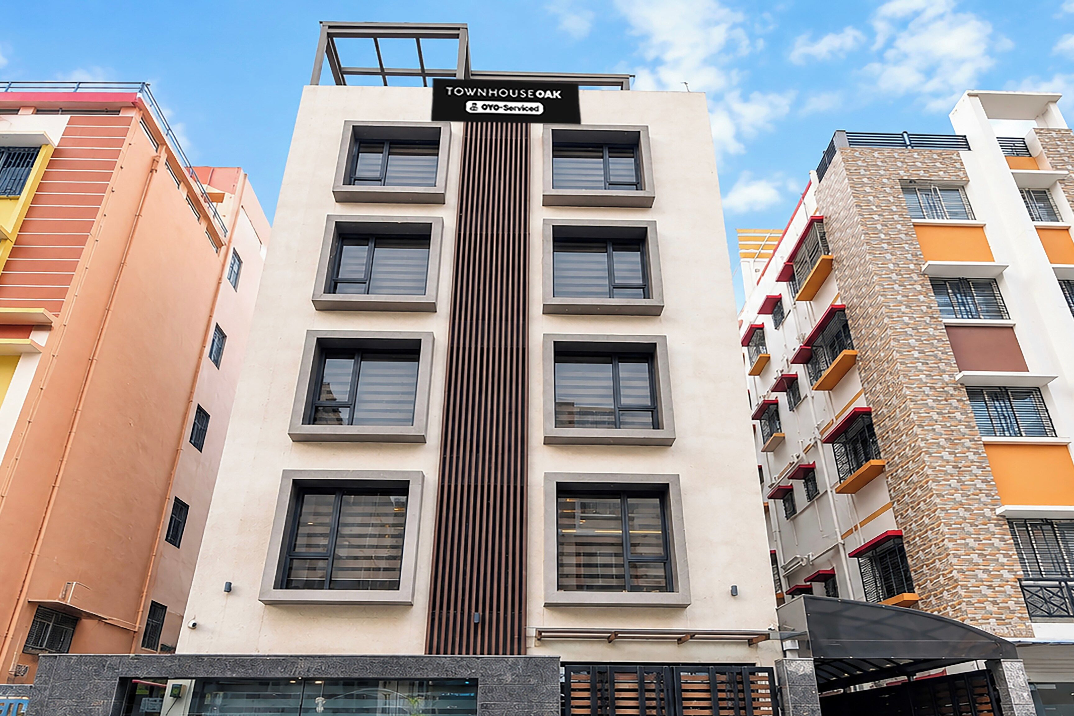 Um edifício de vários andares com uma placa que diz 'TOWNHOUSE OAK' e 'Oyo-Service'.
