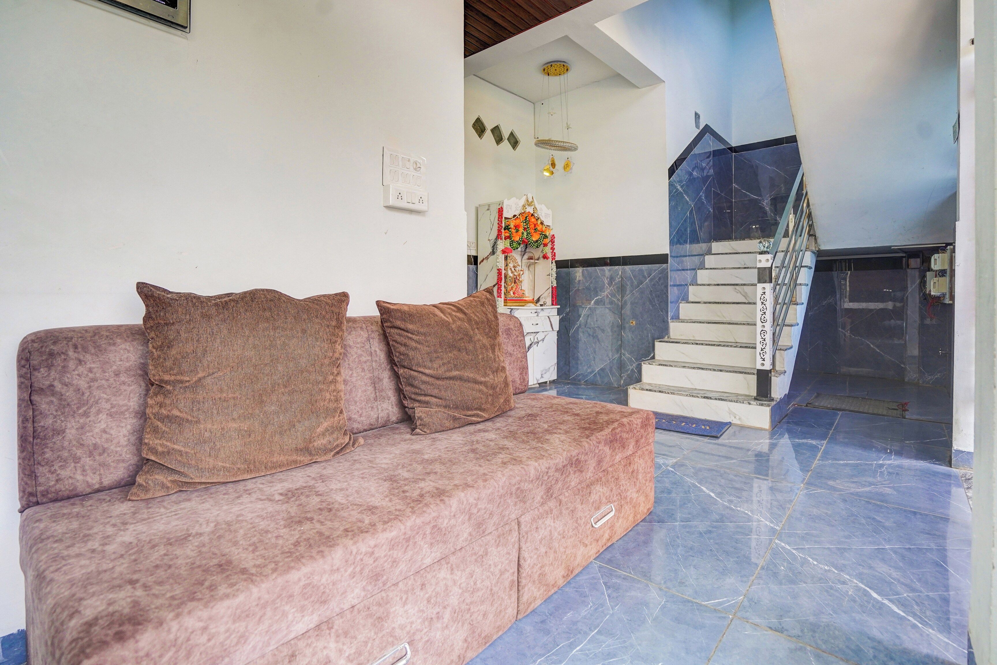 Sala de estar com sofá, escada e tomada elétrica na parede.