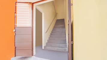 Escada que leva a um andar superior, com corrimão de um lado e porta do outro.