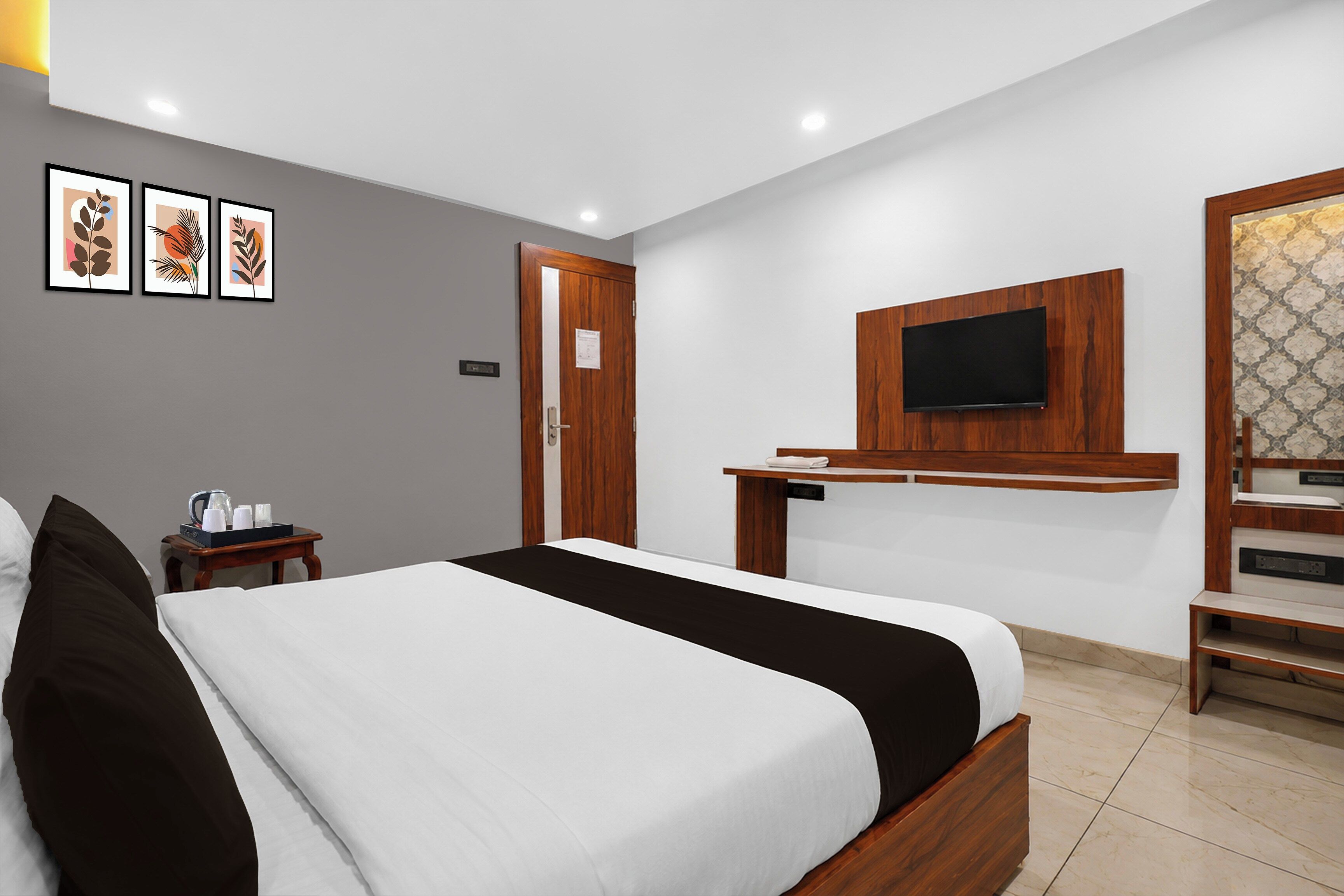 Quarto de hotel com cama, mesa de cabeceira, televisão e uma obra de arte na parede.