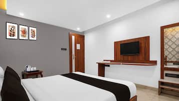 Quarto de hotel com cama, mesa de cabeceira, televisão e uma obra de arte na parede.