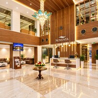 Um hall de hotel com balcão de recepção, área de estar e um lustre grande.