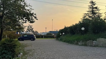 Uma entrada pavimentada que leva a um edifício com um carro estacionado.