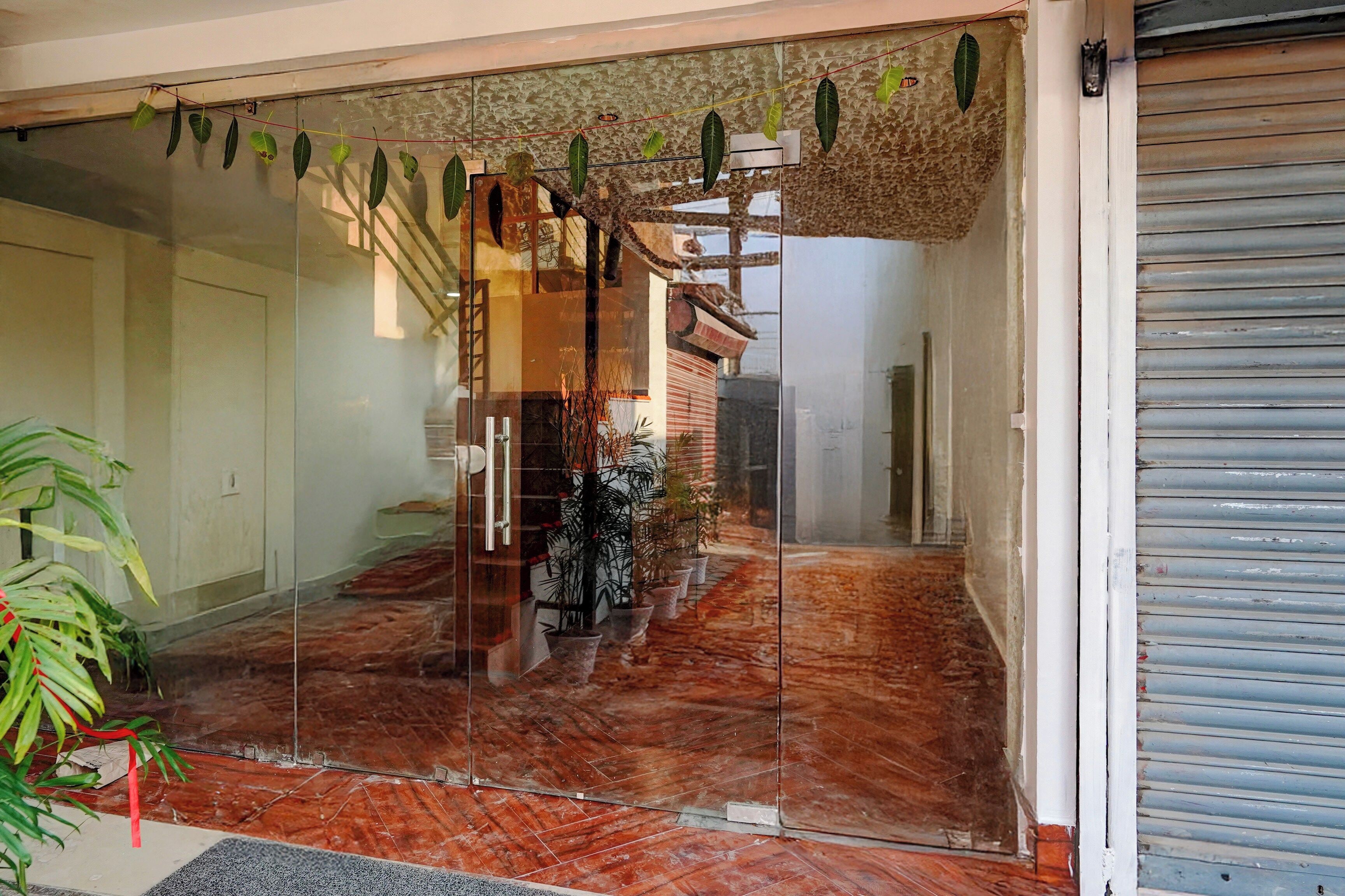 Entrada com porta de vidro, piso de madeira e portão de metal.