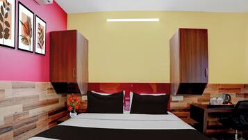 Quarto de hotel com cama, escrivaninha com cafeteira e parede decorada com obras de arte.