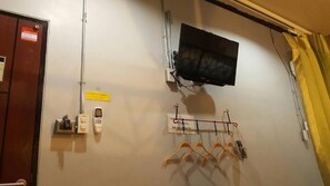 Quarto com televisão na parede, telefone e placa indicando para não deixar o aparelho.