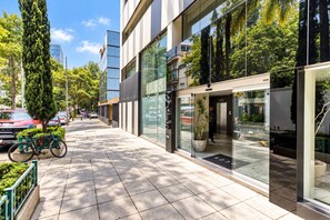 Um edifício moderno com fachada de vidro, uma bicicleta estacionada na frente e um céu claro.