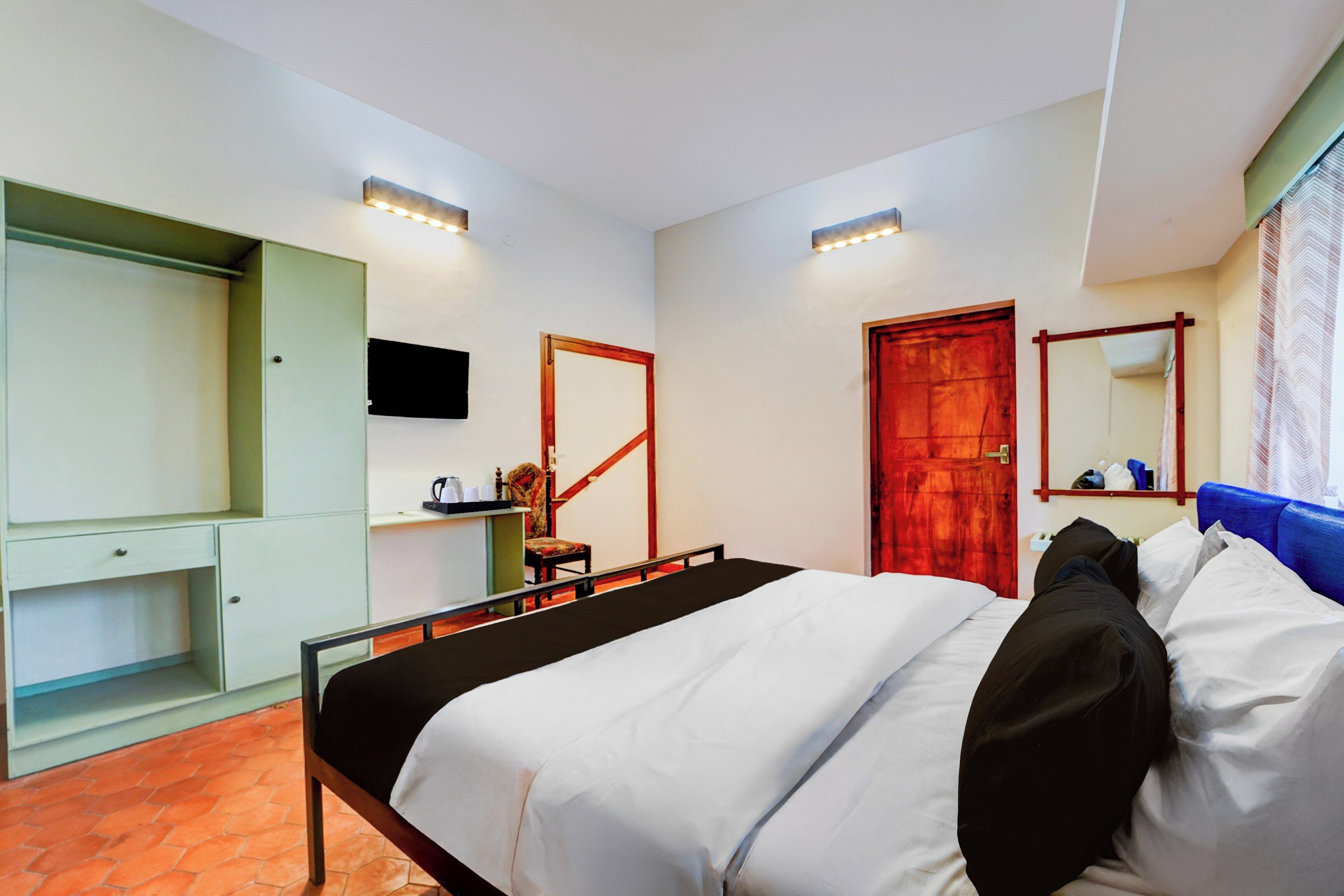 Um quarto com uma cama, uma escrivaninha, uma cadeira, um guarda-roupa e uma televisão.