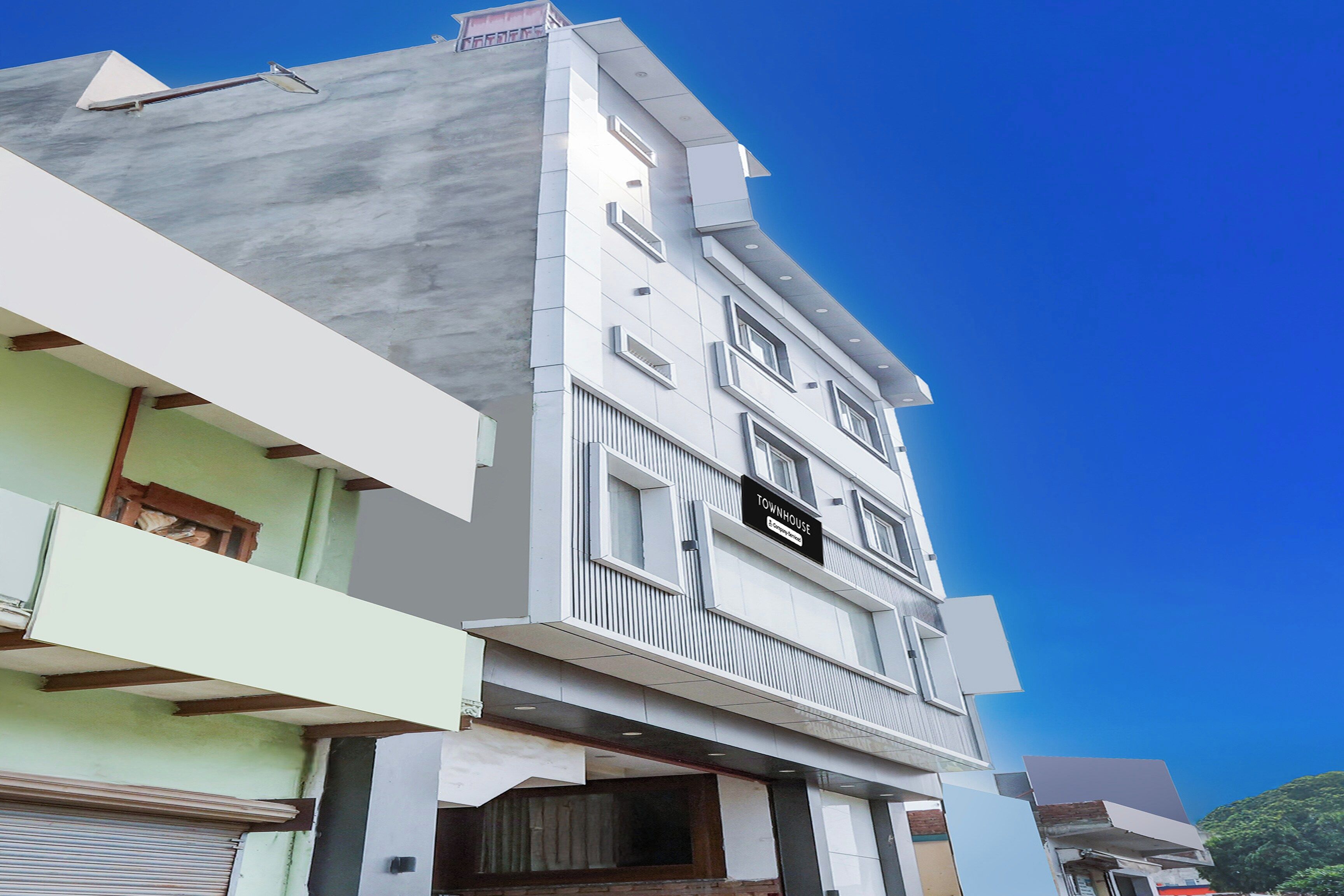 Um edifício de vários andares com uma placa de destaque 'TOWNHOUSE', grandes janelas e telhado plano.
