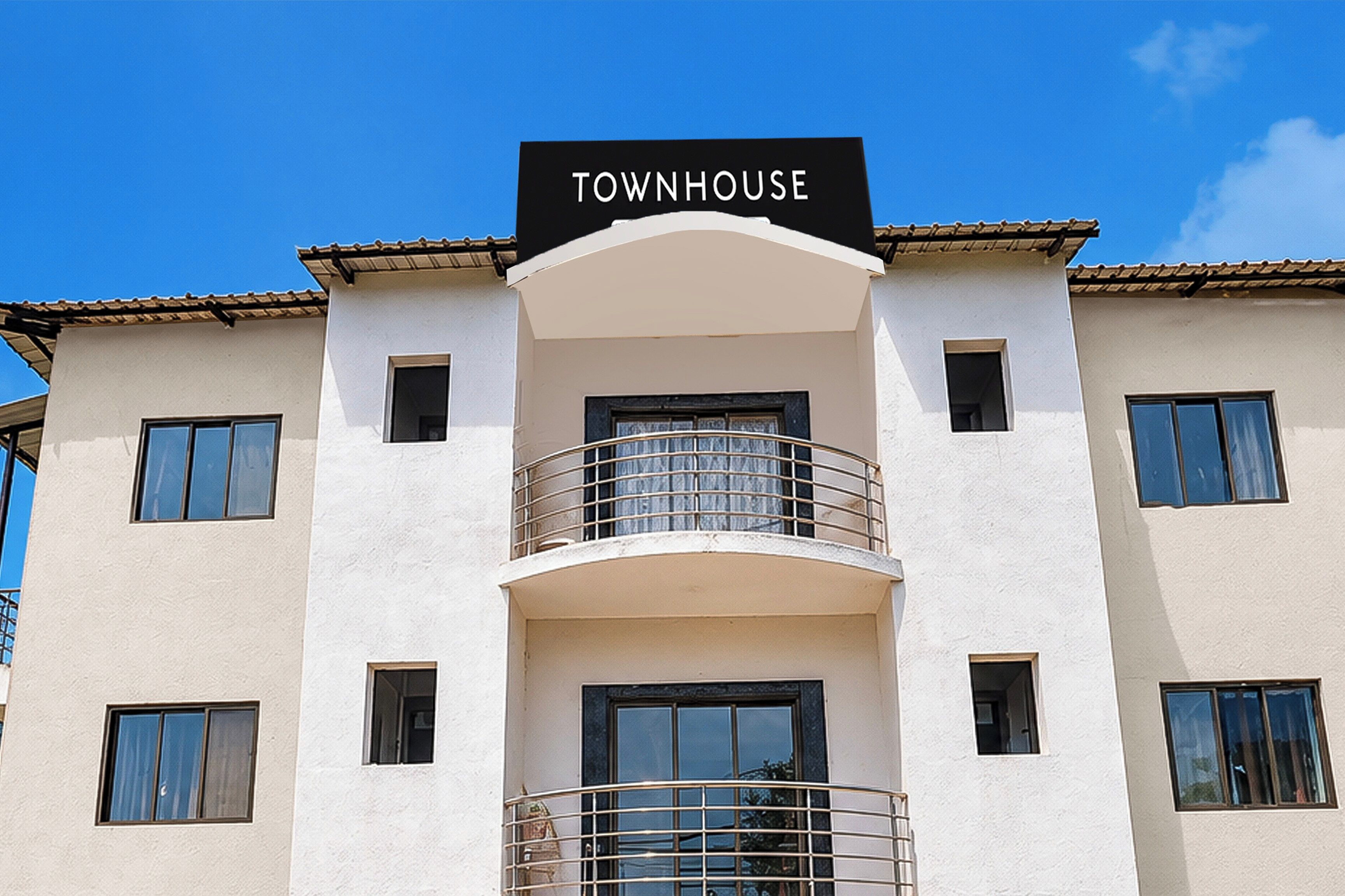 Um edifício de vários andares com uma placa acima da entrada que diz 'TOWNHOUSE'.