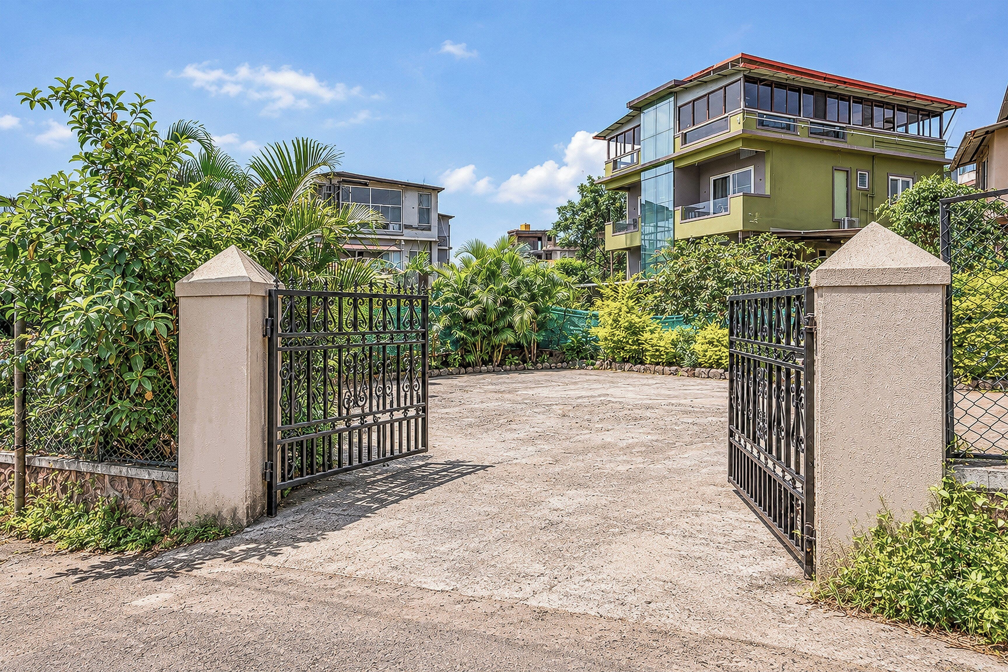 Portão fechado para uma área residencial com várias casas de dois andares, cercada por vegetação.