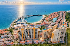 Resort costeiro com marina central, vilas na praia e hotéis altos.
