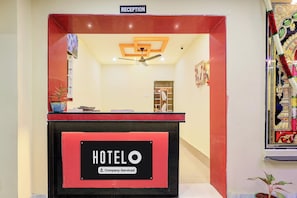 Um balcão de recepção com uma placa indicando 'HOTELO Company Serviced' e uma placa 'RECEPTION' em cima.