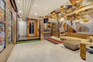 Um hall moderno com balcão de recepção, um sofá, uma mesa de centro e um tapete estampado.