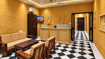 Um saguão de hotel com balcão de check-in, área de estar e mesa de recepção.