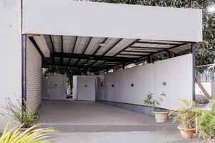 Área de estacionamento coberta e ao ar livre, com piso de concreto e cobertura metálica.