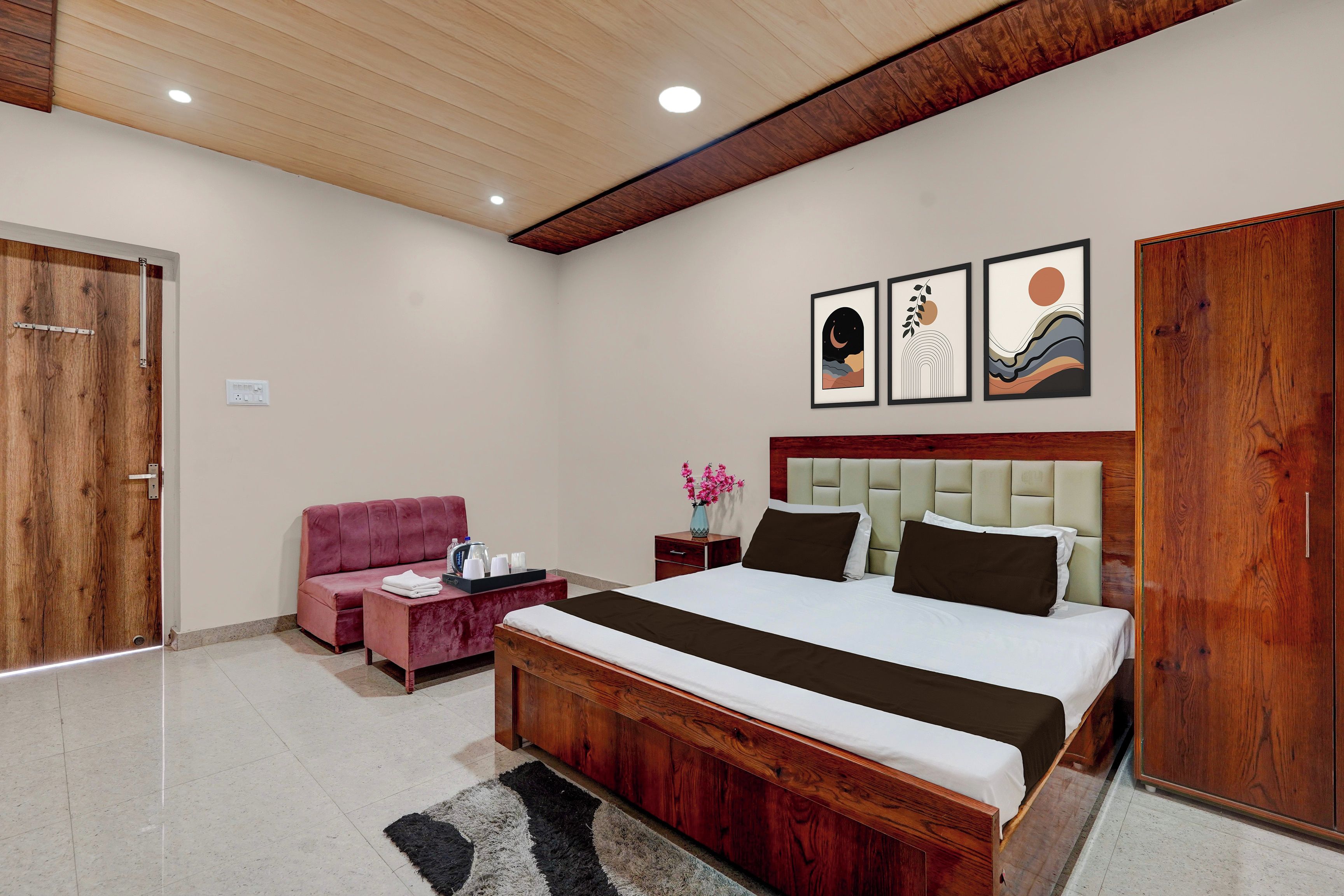 Quarto de hotel com uma cama grande, um sofá, uma mesa de cabeceira e obras de arte na parede.