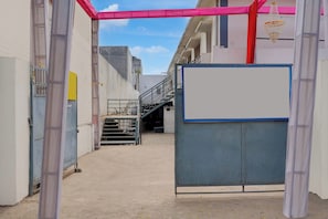 Um corredor em estilo industrial com um portão de metal, escadas e uma lousa em uma parede.