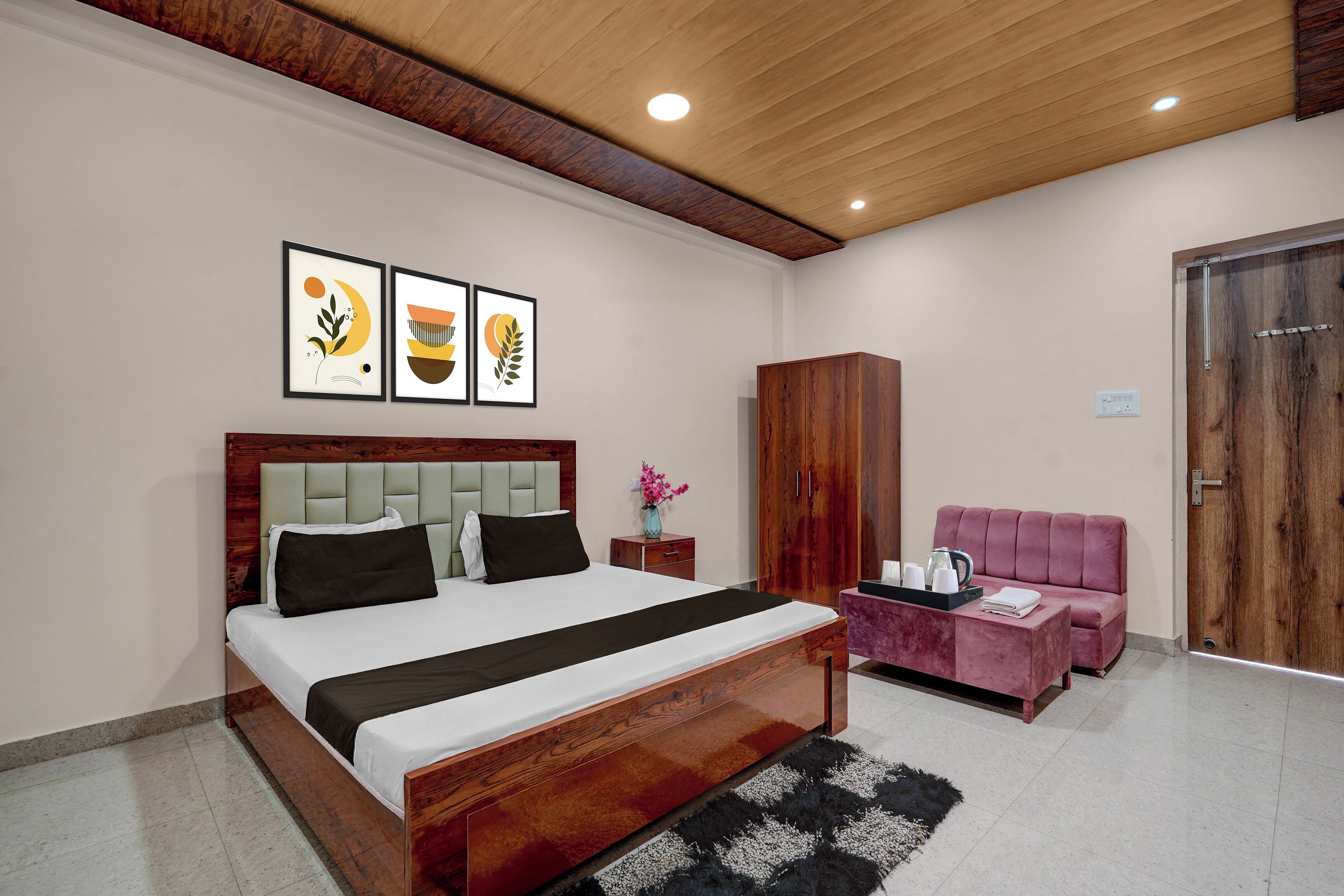 Quarto moderno com cama de madeira, armário de madeira, sofá rosa e três obras de arte emolduradas na parede.