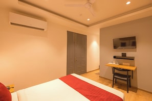 Quarto com cama, escrivaninha, cadeira, televisão e guarda-roupa.