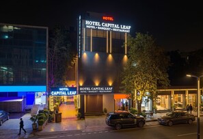 Um hotel com uma placa grande que diz 'HOTEL CAPITAL LEAF HOTEL BANQUET RESTAURANT'.