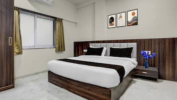Quarto moderno com cama grande, mesa de cabeceira, vaso com flores e obras de arte na parede.