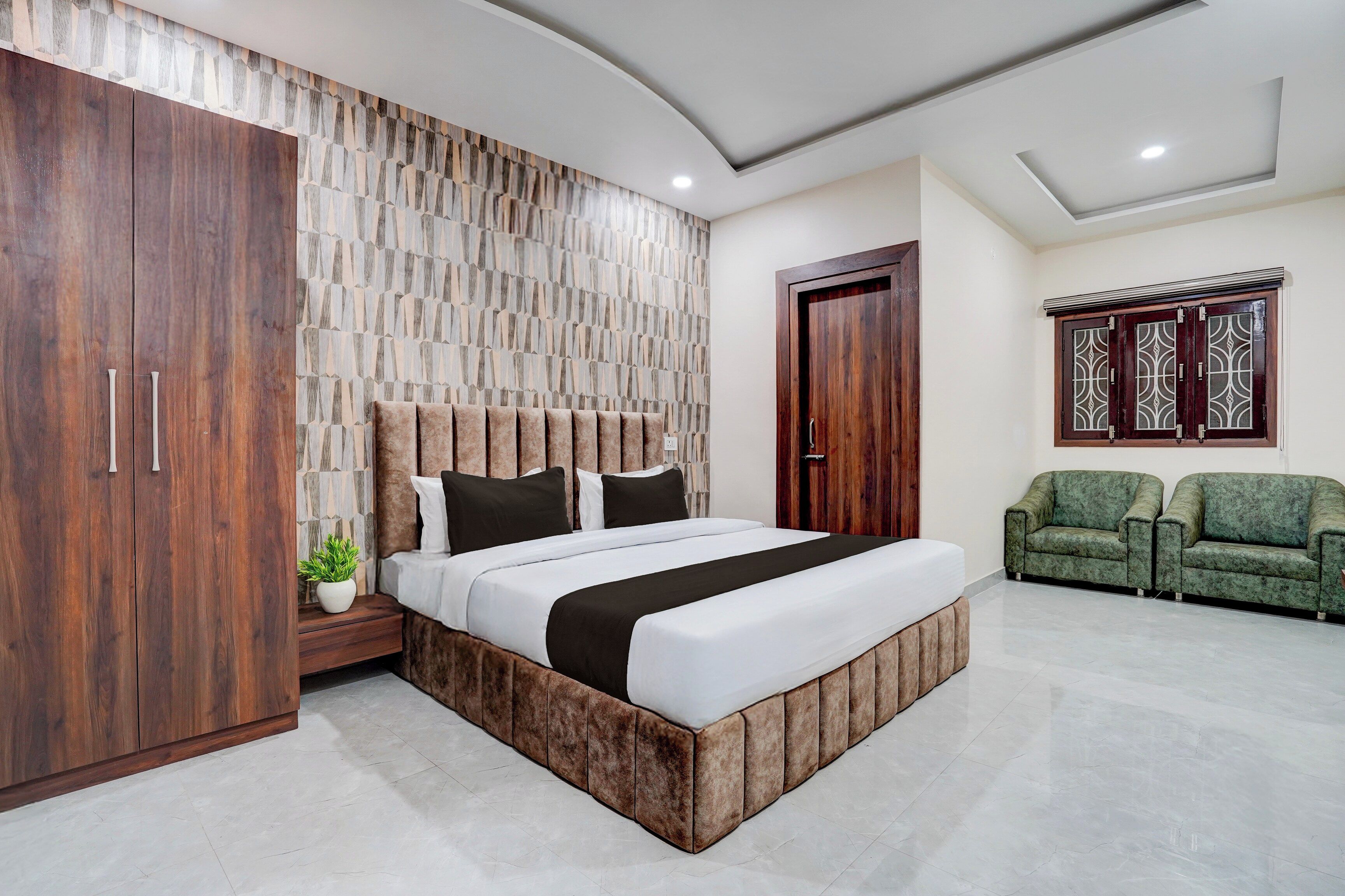 Quarto moderno com cama grande, guarda-roupa de madeira e sofá verde.