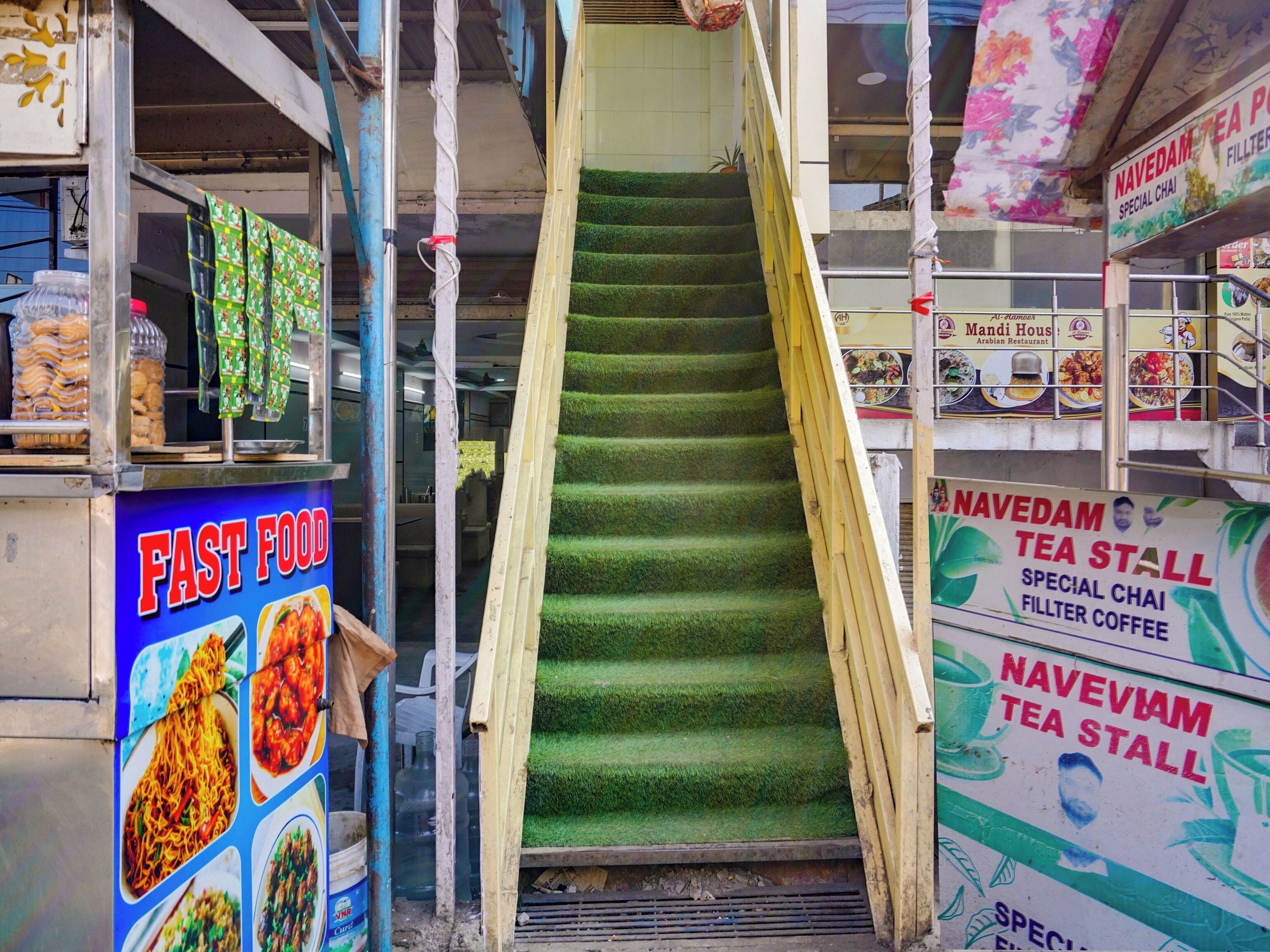 Escadaria que leva a um quiosque de chá, com uma placa anunciando comida rápida e café chai filtrado especial.