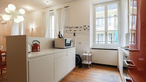 Cozinha moderna com micro-ondas, chaleira e janela com vista para o edifício.