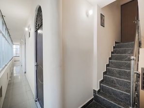Um corredor com escadas, uma porta e uma janela.