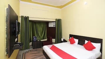 Quarto de hotel com cama, televisão, escrivaninha e cadeira.