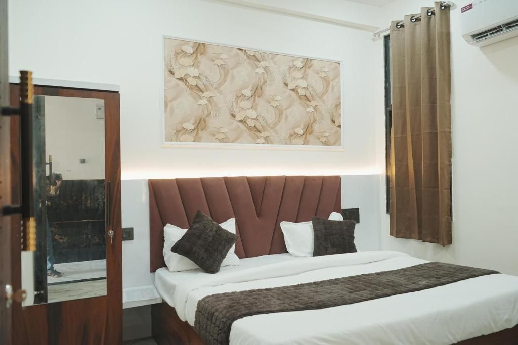 Quarto com cama, cabeceira, obra de arte na parede e janela com cortinas.