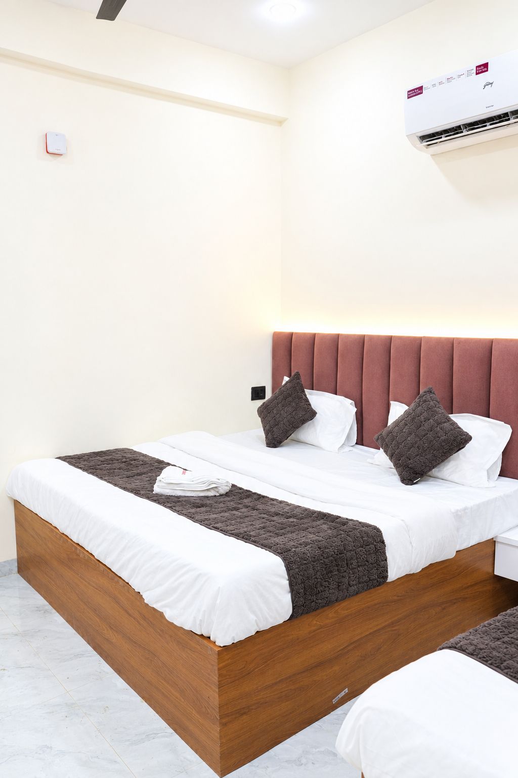 Cama bem arrumada, com estrutura de madeira, encosto e dois travesseiros.