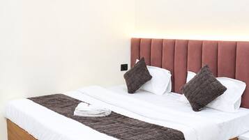 Cama bem arrumada, com estrutura de madeira, encosto e dois travesseiros.