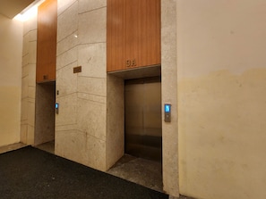 Um elevador com mostrador digital, um painel de madeira acima e uma placa indicando o número do andar.