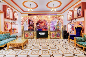 Um quarto ricamente decorado, com sofás ornamentados, uma vitrine central e piso estampado.