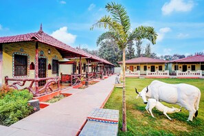 Um edifício tradicional com telhado de telhas, um caminho que leva a uma área de estar e uma estátua de uma vaca com um bezerro.