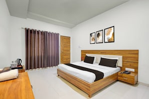 Quarto de hotel moderno com cama de madeira, mesa de cabeceira, comodinho e máquina de café.