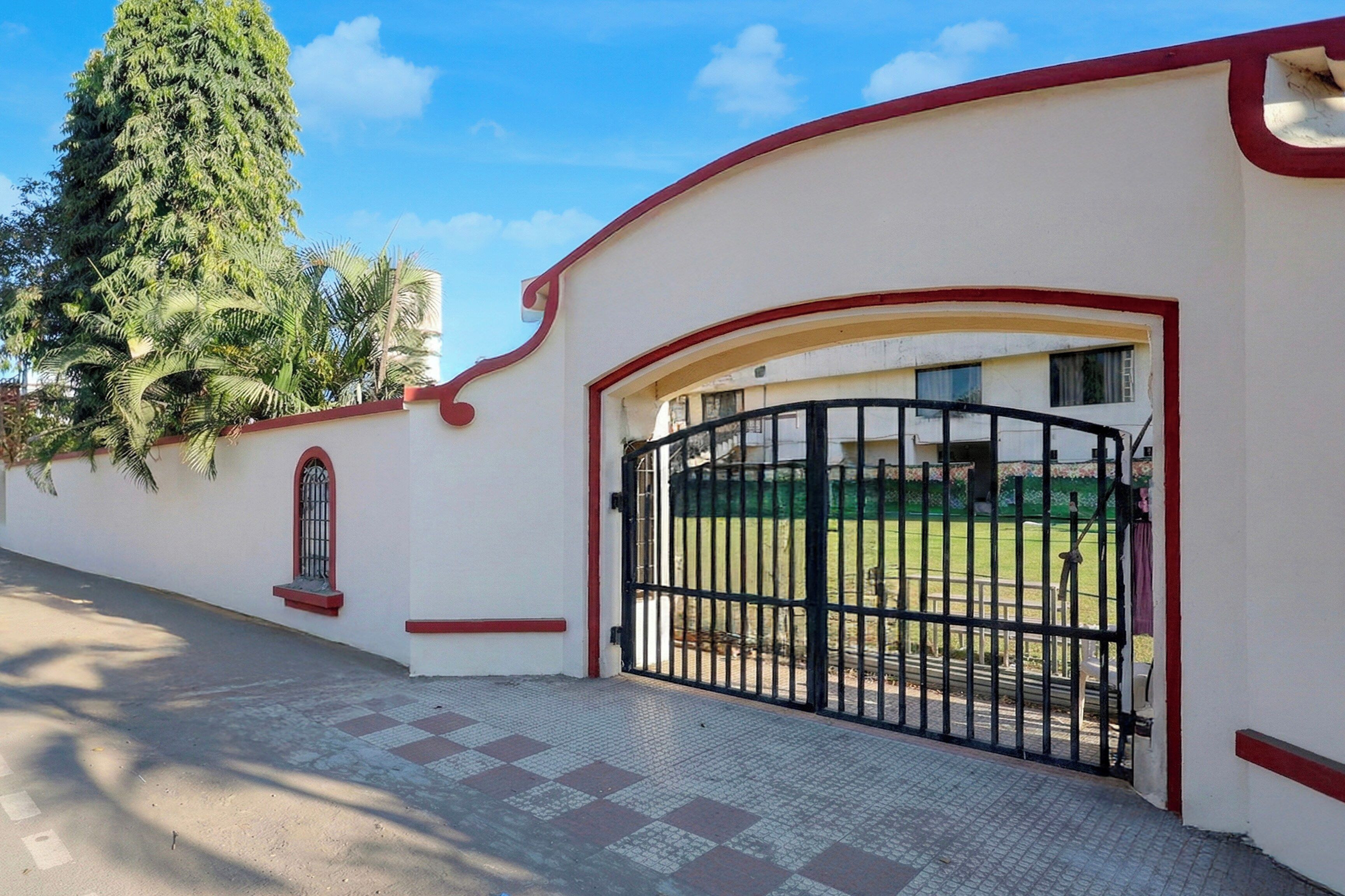 Uma entrada com portão e um caminho de paralelepípedos até um edifício.