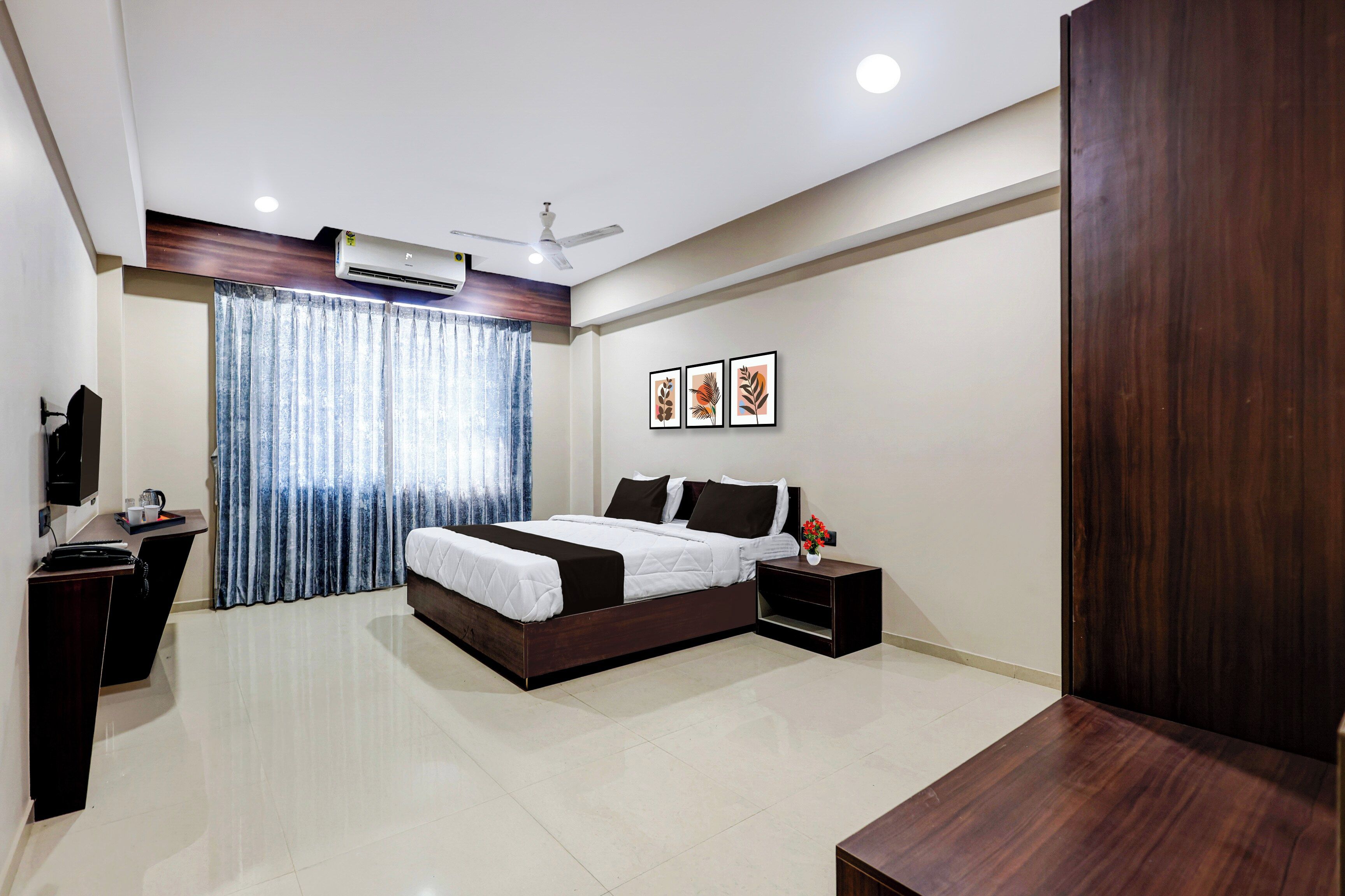 Quarto de hotel moderno com cama, mesa de cabeceira e escrivaninha com cadeira.