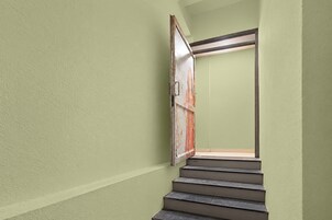 Escadaria que leva a um quarto com parede verde e porta aberta.