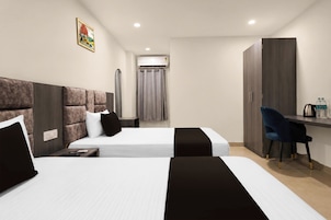 Quarto de hotel com duas camas, uma escrivaninha, uma cadeira, um ar condicionado e um guarda-roupa.