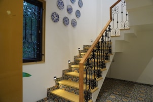 Uma escadaria com grades pretas elaboradas e piso estampado.