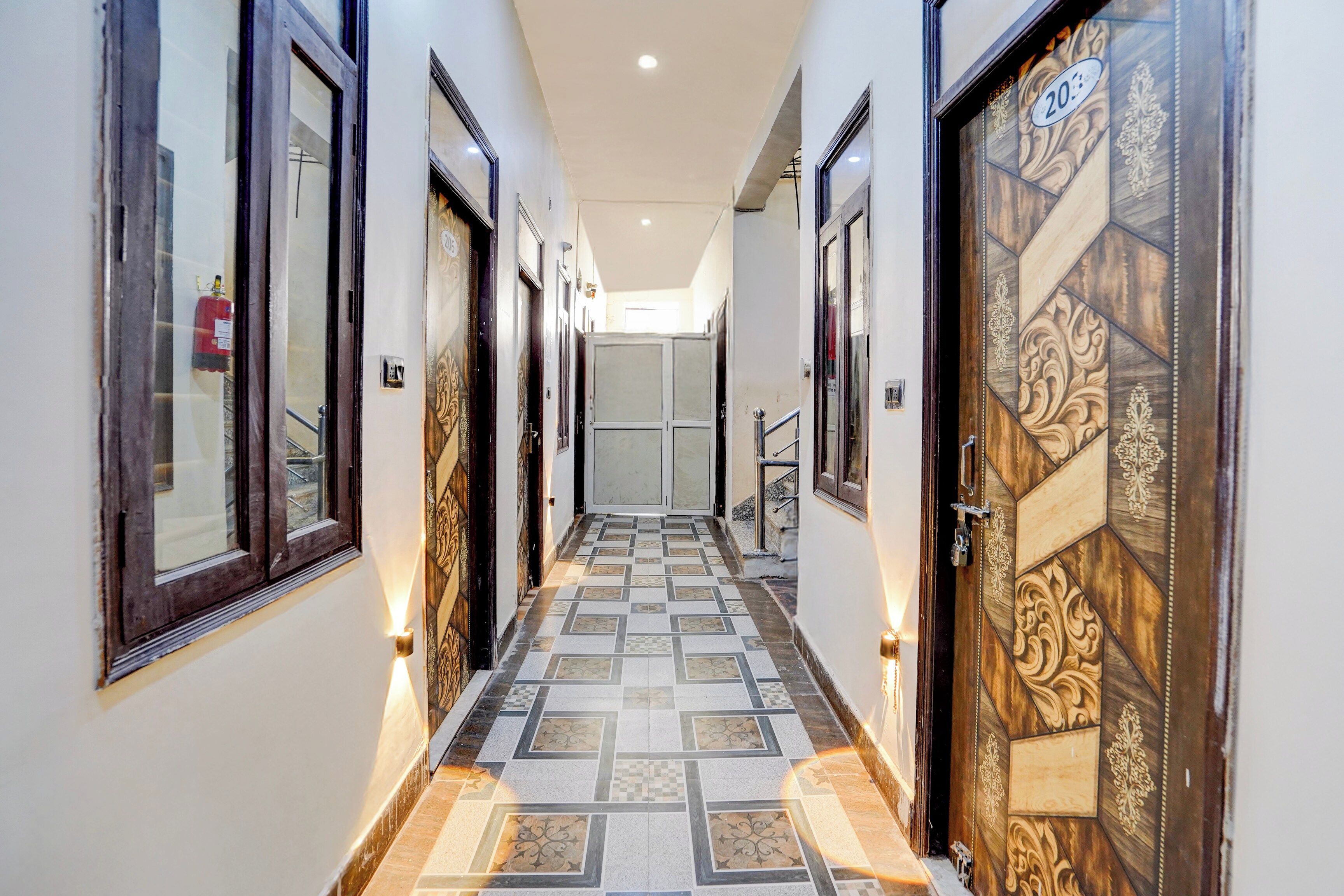 Corredor com piso estampado, portas com detalhes decorativos e luminária na parede.