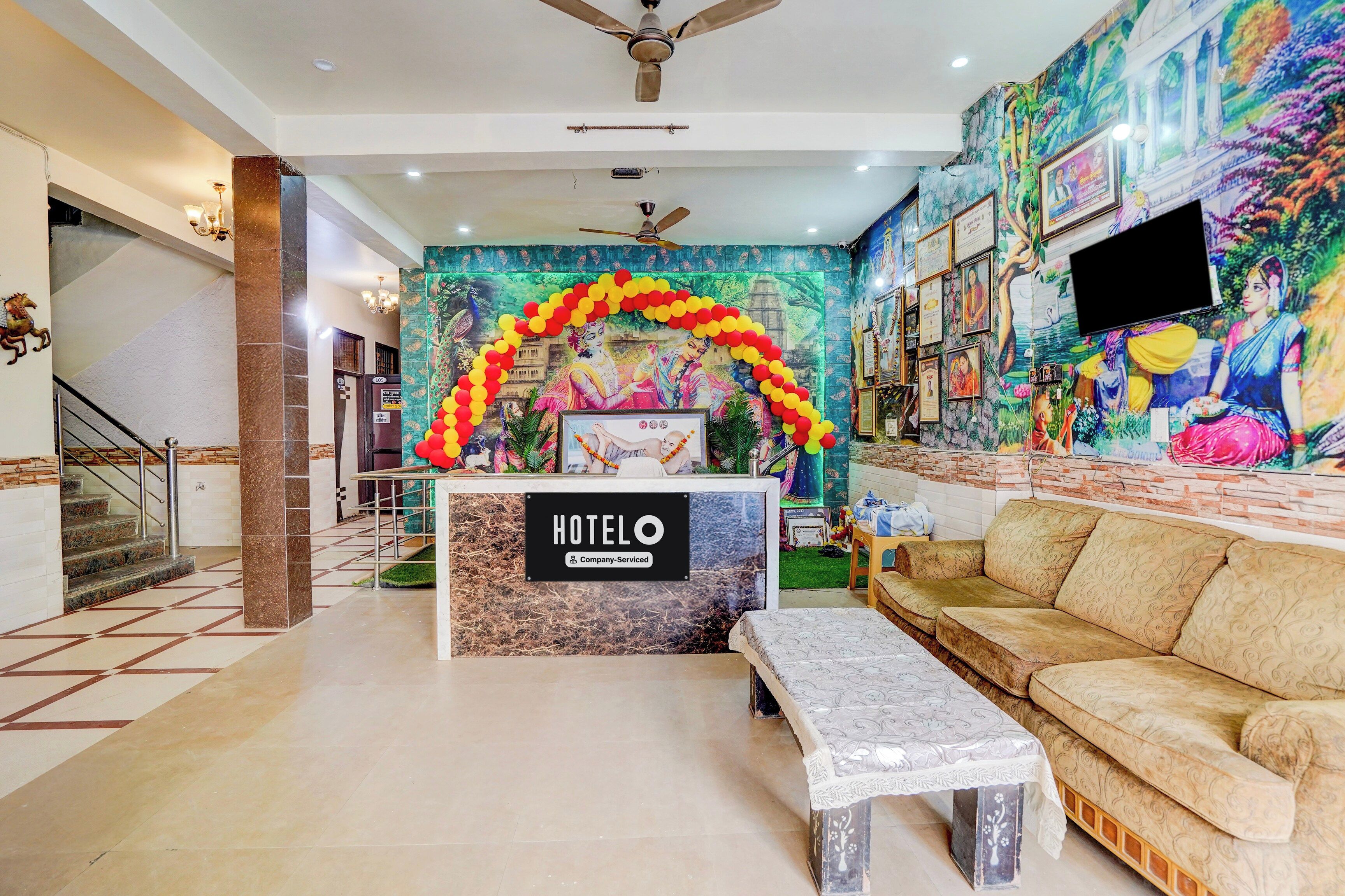 Uma área de recepção de hotel com balcão, sofá, banco e escada.