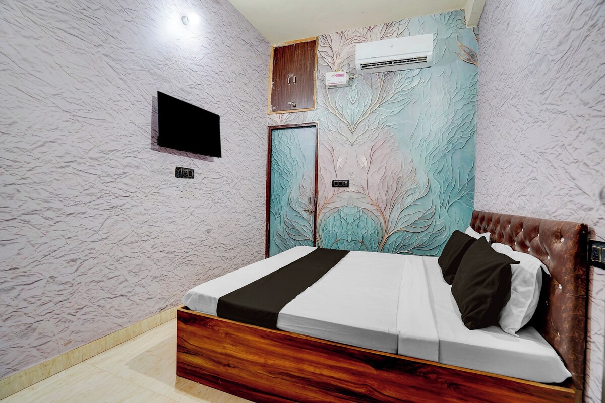 Quarto com cama, televisão, ar condicionado e decoração na parede.