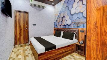 Quarto de hotel com cama de madeira, televisão fixada na parede e design de parede estampado.