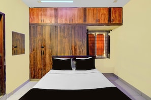 Quarto com cama, guarda-roupa e janela.