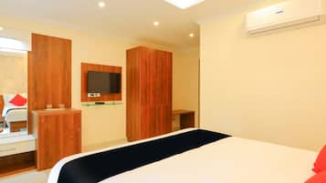 Quarto de hotel com cama, televisão na parede, guarda-roupa de madeira e unidade de ar condicionado.